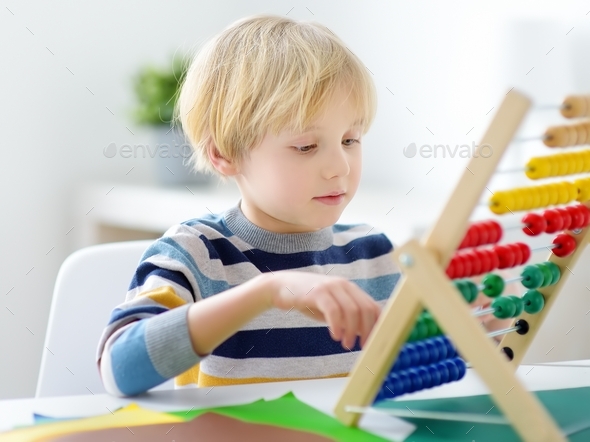 Elementary student boy doing homework at home. Child learning to count ...