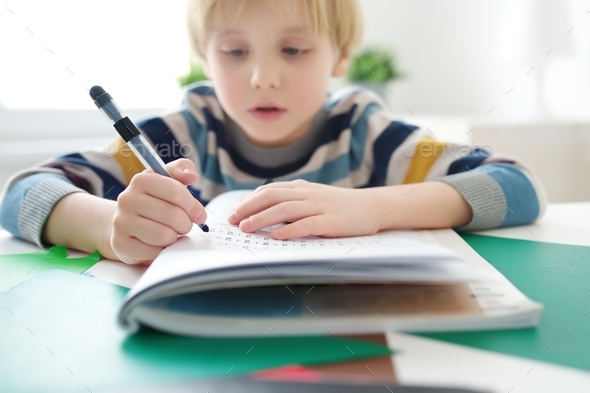 Elementary student boy doing homework at home. Child learning to count ...