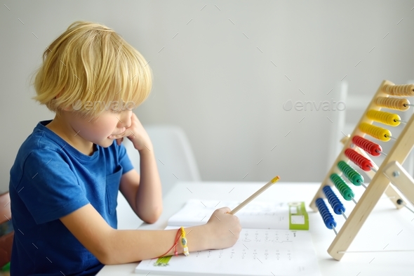 Elementary student boy doing homework at home. Child learning to count ...