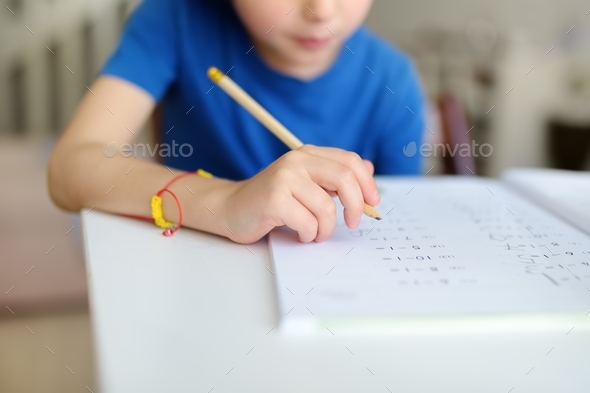 Elementary student boy doing homework at home. Child learning to count ...