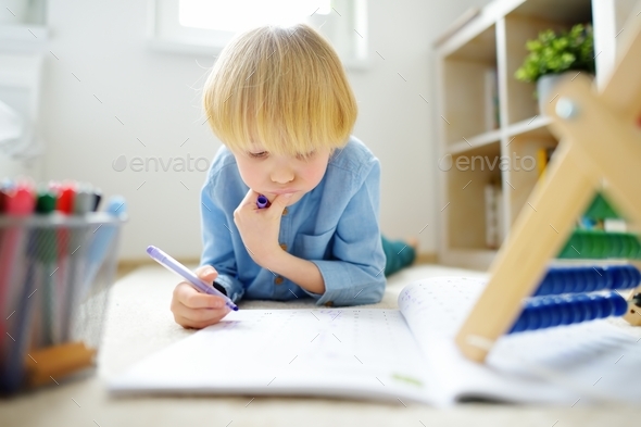 Elementary student boy doing homework at home. Child learning to count ...