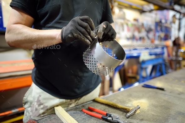 Metalwork craftsman making handmade lamp at workshop. Man worker screws ...