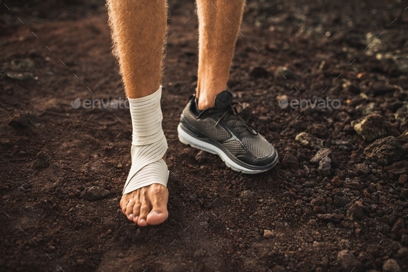 Man's ankle in compression bandage. Leg injury while trail running ...