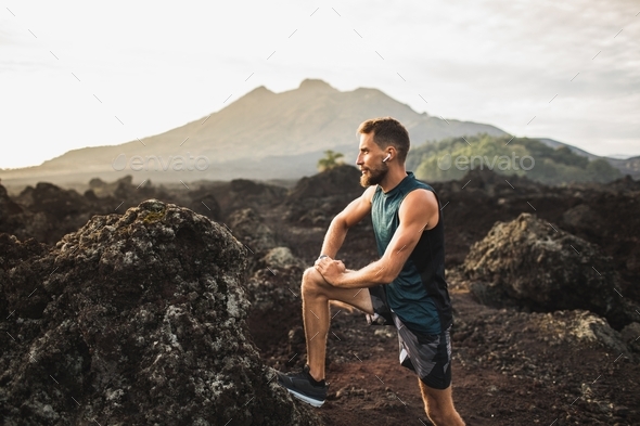 Young hipster runner with beard stretching and warming-up for trail ...