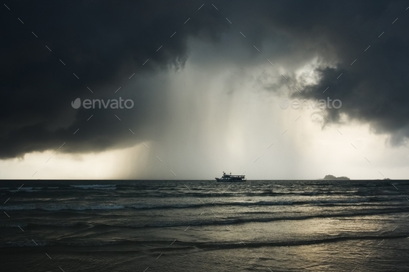 Dramatic seascape with storm, rain and dark clouds. Boat sailing in bad ...