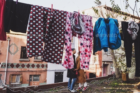 Young couple having fun in drying laundry hanging at old streets of ...