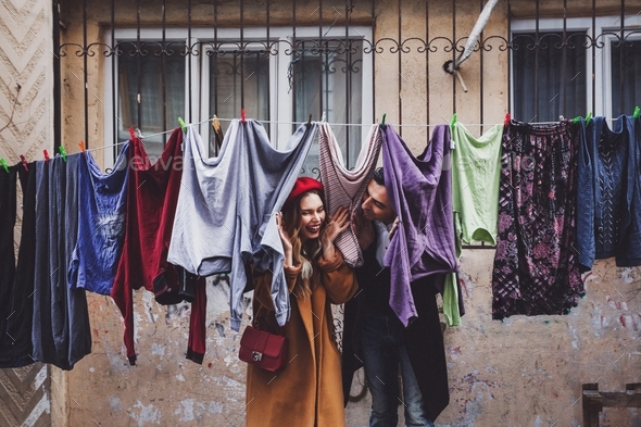 Young couple having fun in drying laundry hanging at old streets of ...