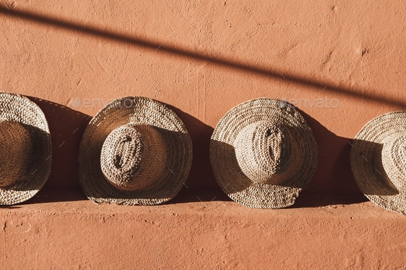 Wicker straw hats on background of terracotta color wall in Morocco ...