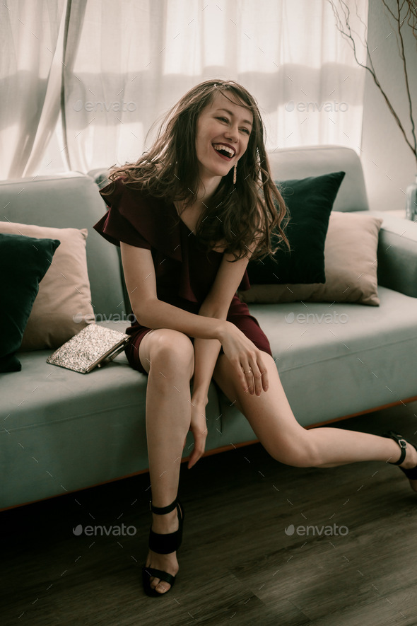 Fancy young lady in a cocktail dress and high heels on the green coach ...