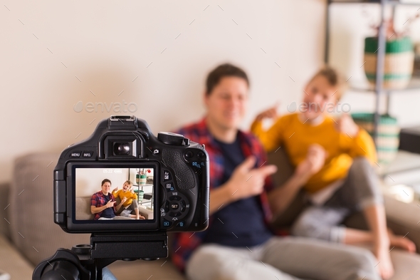 Vlogger family recording social media video while sitting on couch ...
