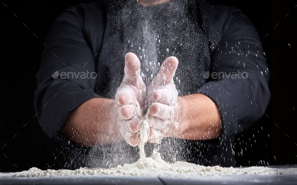 man in black uniform sprinkles white wheat flour in different ...