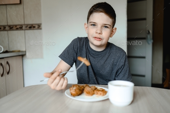 boy eats in the kitchen. fried chicken . Stock Photo by karmanovalive