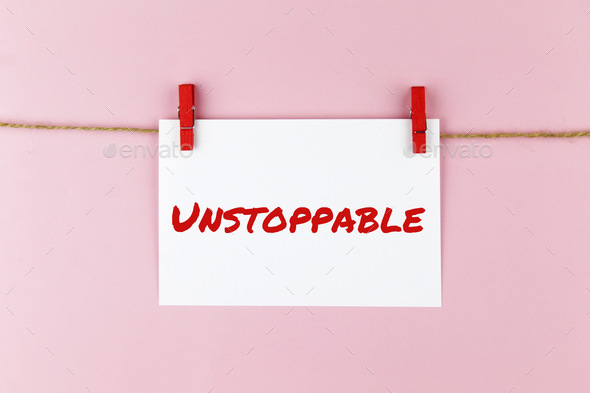 Sticker with the inscription unstoppable hanging on a rope on a pink ...