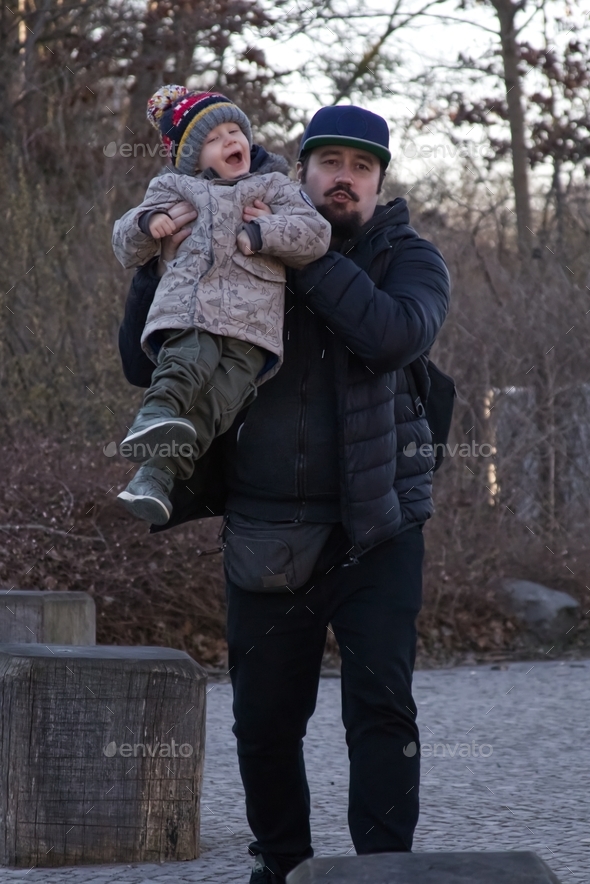 Dad helps son jump from stump to stump Stock Photo by malishevanataly