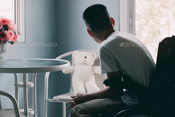 Disabled child on wheelchair talking with a white teddy bear on chair ...
