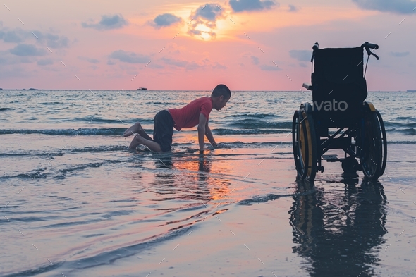 Silhouette of confident disabled child crawling on the beach at sunset ...