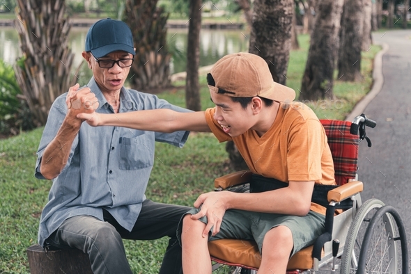 Happy disabled teenager boy on wheelchair smiling face with arm muscle ...