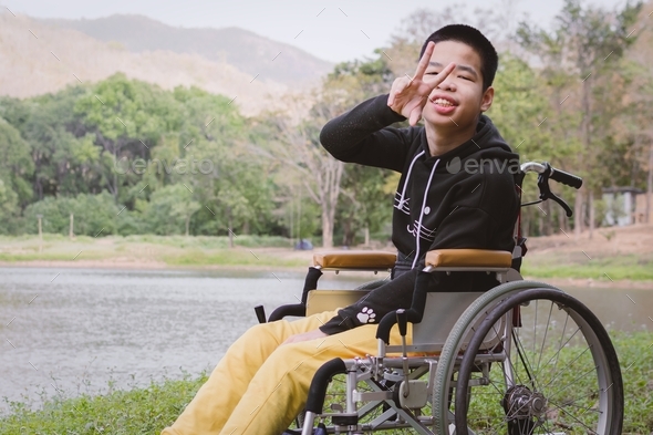 Disabled child on wheelchair raising two fingers means fight in the ...