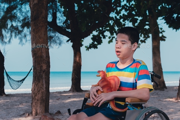 Lonely disabled child on wheelchair hug a dinosaur on summer of sea ...