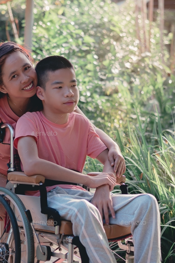 Mother and disabled teenager boy on wheelchair in nature outdoors ...