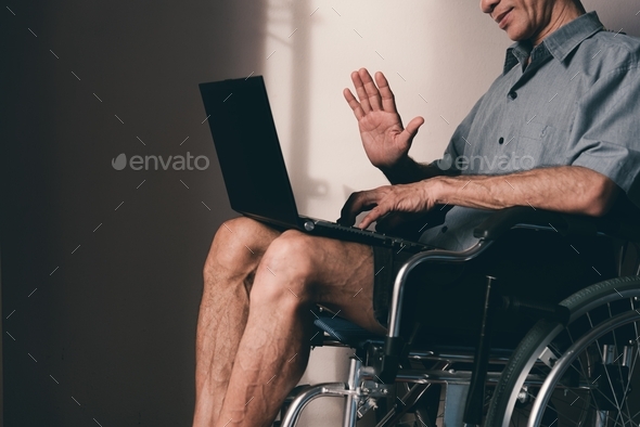 Disabled man on wheelchair using computer. Stock Photo by gaysorn1442