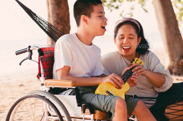 Happy mother and disabled teenager boy on wheelchair smiling face with ...