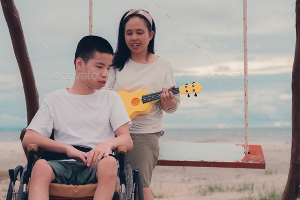 Happy disabled teenager boy on wheelchair and mother relax with music ...