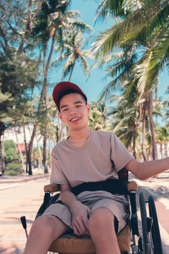 Happy handicapped teenager boy in wheelchair wearing red cap and ...