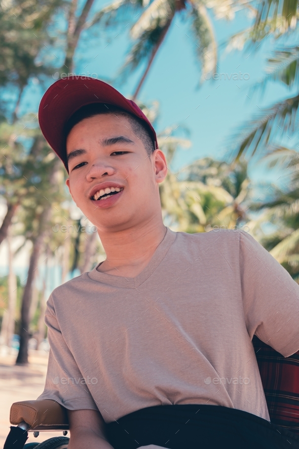 Happy handicapped teenager boy in wheelchair wearing red cap and ...
