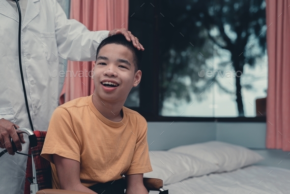 Confident disabled teen boy smiling face and doctor’s hand put his head ...