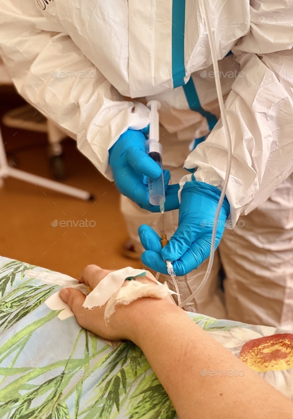 the hands of a nurse in blue gloves hold a syringe and give an ...