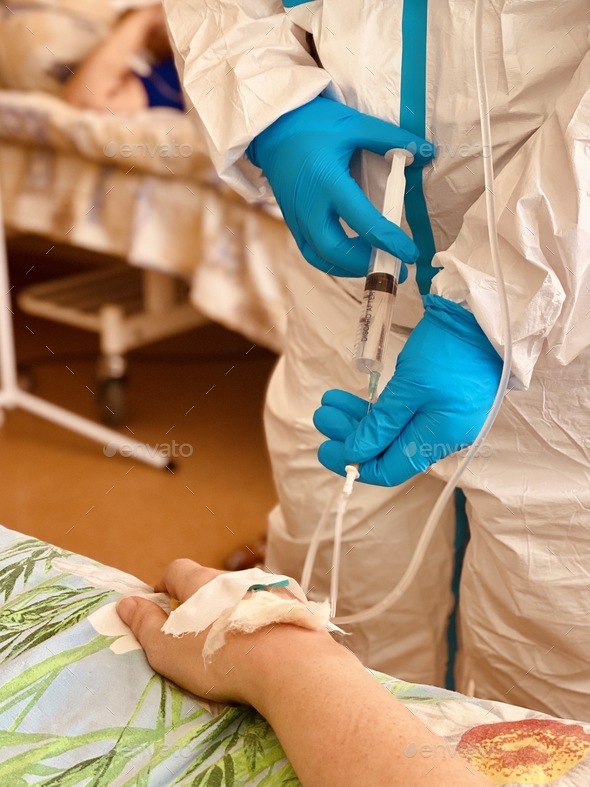 the hands of a nurse in blue gloves hold a syringe and give an ...