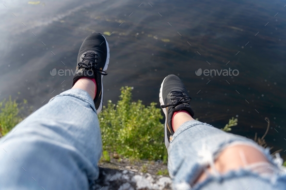 View of legs hanging off from ledge with water at the bottom, point of ...