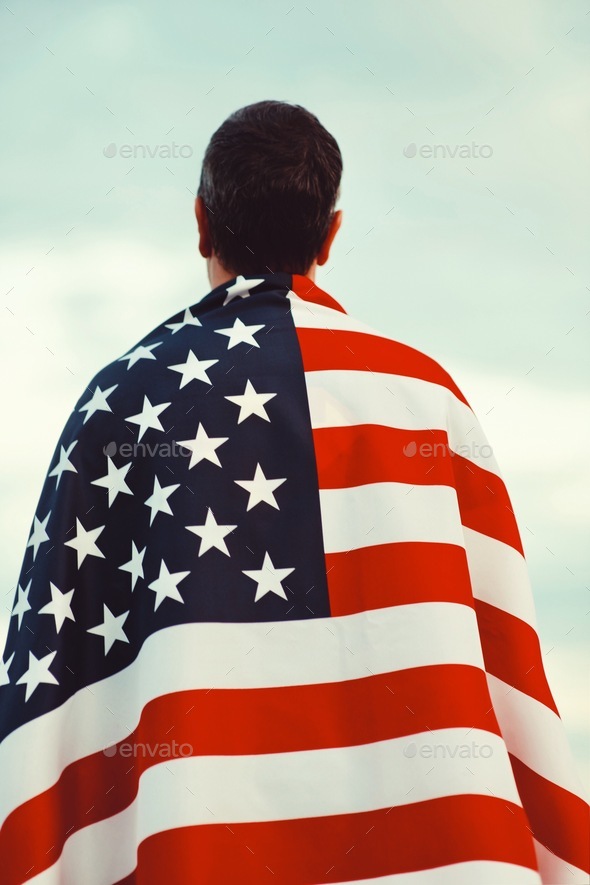 Back view millennial candid authentic man wrapped in US flag looks at ...