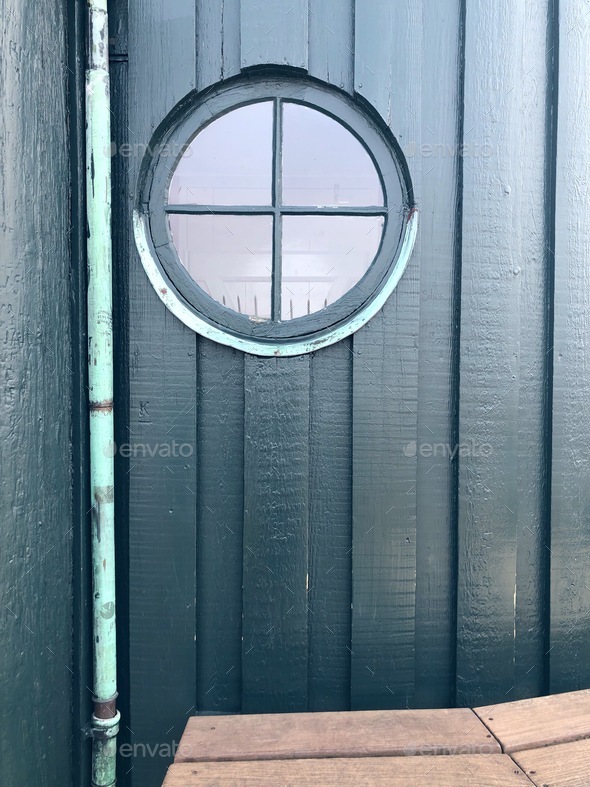 Round window, green wall, and wooden bench Stock Photo by wanaktek