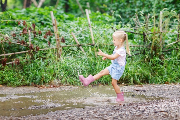 Little girl splashing water from a puddle in summer Stock Photo by ...