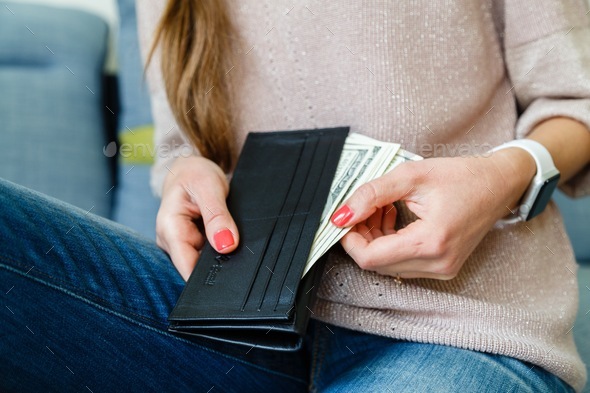 women's hands pull money out of their wallet Stock Photo by alinabuphoto