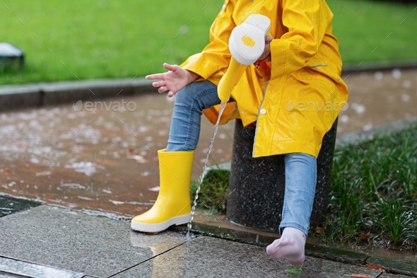 Happy little girl in yellow rain jacket enjoying rainy weather at ...