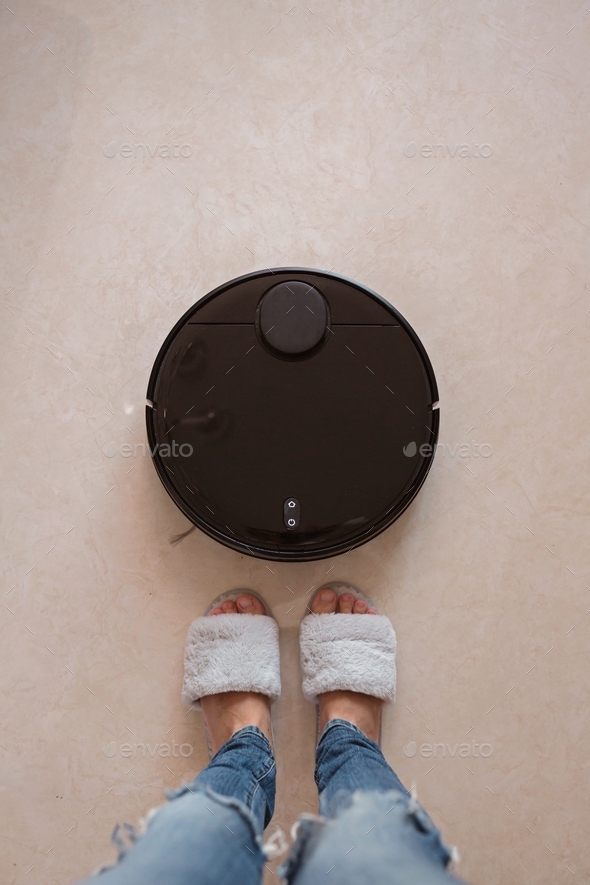 Robotic vacuum cleaner cleaning the room while woman relaxing. Top view ...
