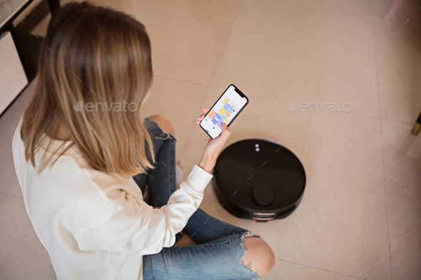 Robotic vacuum cleaner cleaning the room while woman relaxing. Woman ...