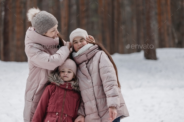 Family winter walk in the forest. Mother and daughter are having fun in ...