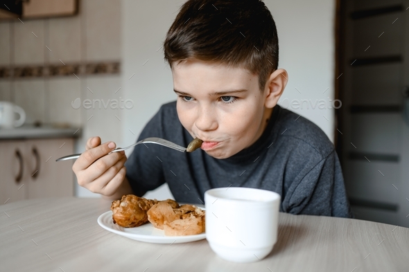 boy eats in the kitchen. fried chicken . Stock Photo by karmanovalive