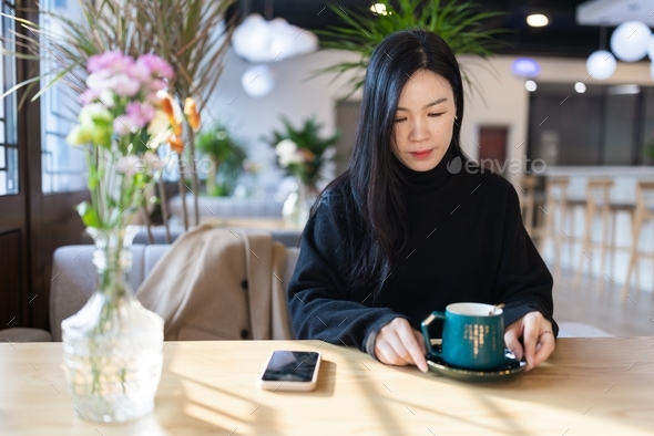 Happy stylish young asian generation z woman drinking coffee in small ...