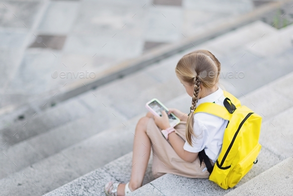 Child using modern technology and chatting with friends outdoor when ...