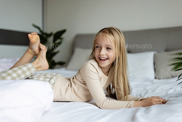 Cute little Caucasian girl with blonde hair wearing pajamas when lying ...
