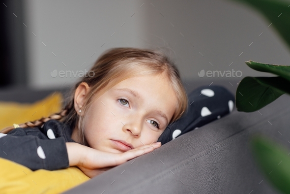School child sitting alone on couch at home during coronavirus pandemic ...