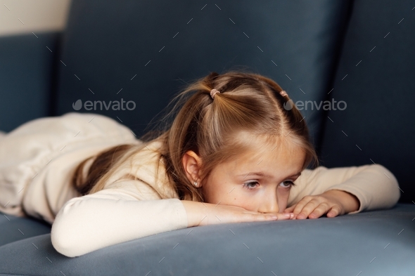 School child lying alone on blue couch at home during coronavirus ...