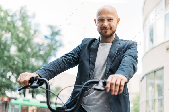 Adult friendly bald bearded man in blue suit on bicycle in the city ...