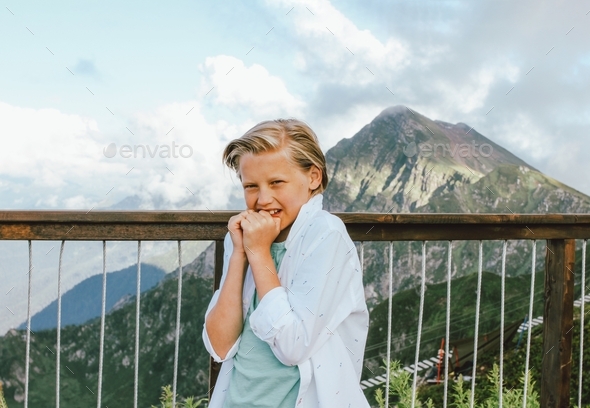 Blonde cold boy on observation deck on background of wonderful view of ...