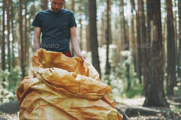 Man volunteer cleaning forest of garbage in large bag Stock Photo by ...